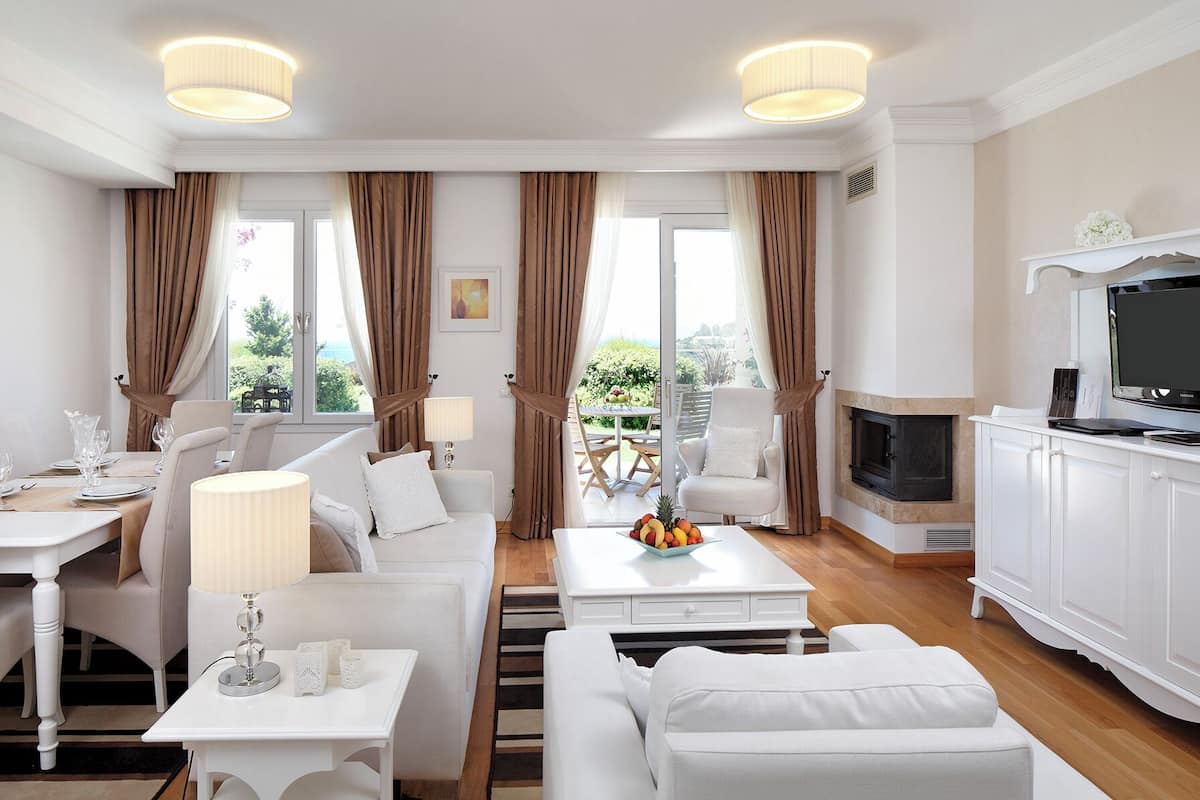 Quarto de hotel moderno com área de refeições, sala de estar com lareira e televisão.
