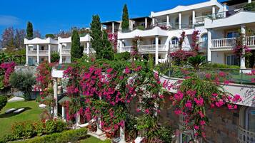 Um hotel com vários andares, varandas, jardins exuberantes e plantas floridas.