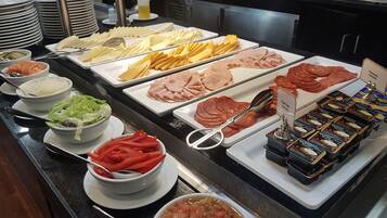 Buffet com diversos alimentos, incluindo carnes fatiadas, queijos e vegetais.