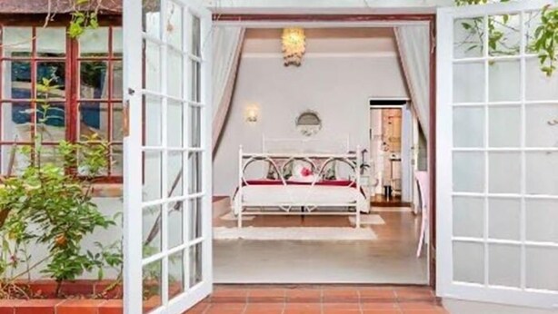 Quarto com cama, porta branca e janela com vista para o exterior.