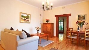 Sala de estar com sofá, mesa de jantar de madeira, cadeiras e um candelabro.