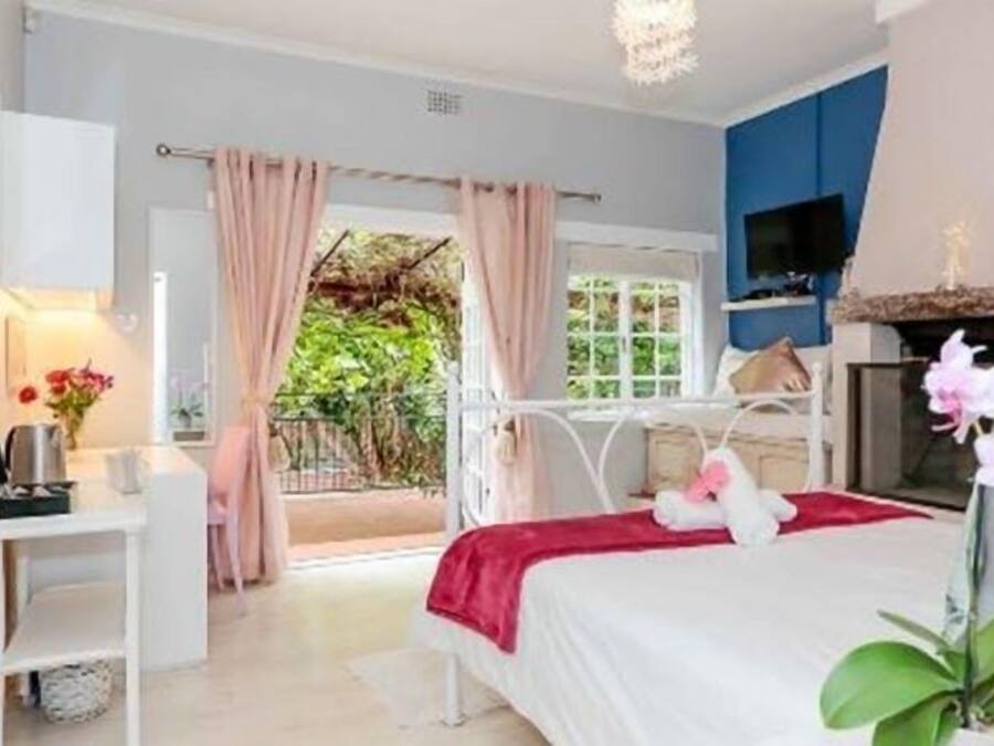 Quarto com cama, televisão, escrivaninha e janela com cortinas.