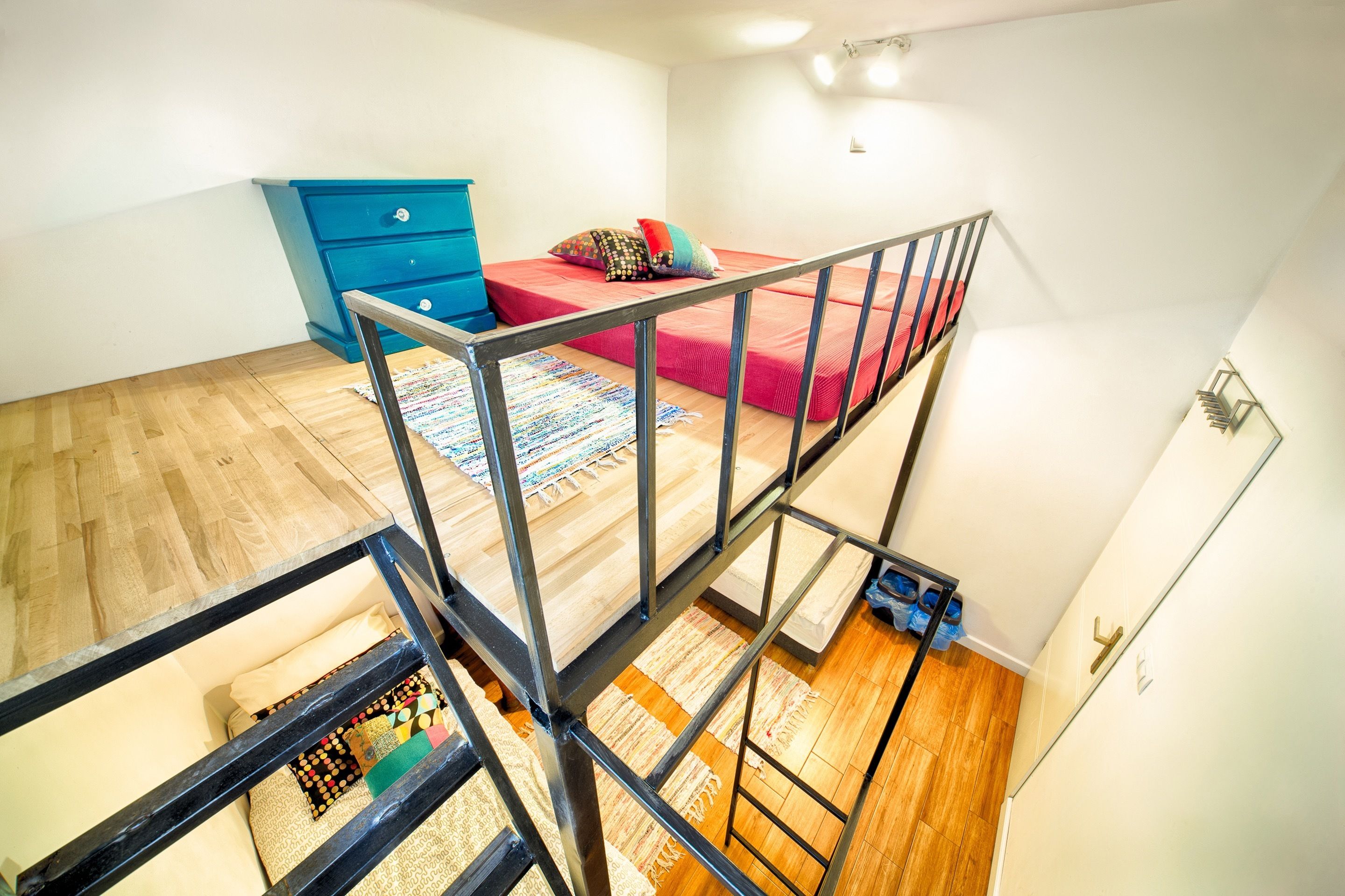 Quarto com beliche, cómoda azul e chão de madeira.