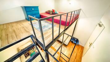 Quarto com beliche, cómoda azul e chão de madeira.