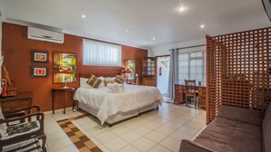 Quarto de hotel com cama grande, divisória de madeira, escrivaninha e cadeira.