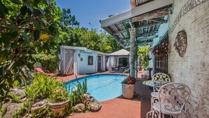 Um quintal com piscina, área de estar externa e varanda coberta.