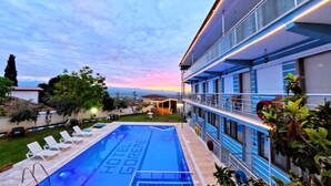 Um hotel com piscina, área de estar externa e vista para as montanhas.