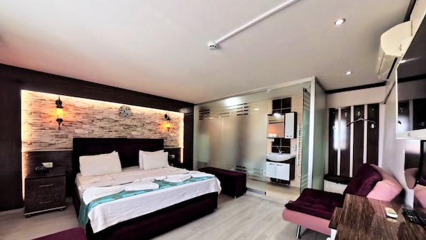 Quarto moderno com cama, mesas de cabeceira, toucador e um espaço de estar.