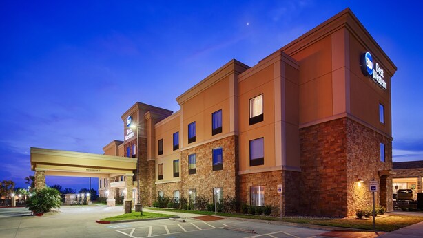 Um hotel com design moderno, exibindo uma placa chamativa da 'Best Western', uma entrada coberta e um estacionamento.
