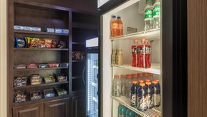 Espaço de armazenamento com prateleiras contendo lanches, bebidas engarrafadas e outras bebidas.