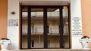 Entrada de um hotel com uma placa indicando "HD DOMUS" e a descrição de comodidades como "apartamentos elegantes, quartos mobiliados, internet, WiFi e aceita animais de estimação".