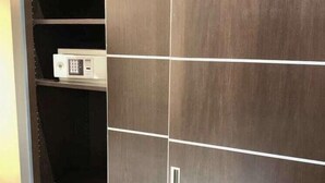 Um guarda-roupa com várias prateleiras e gavetas, um painel de controle em uma das prateleiras, e um objeto retangular pequeno na prateleira superior.