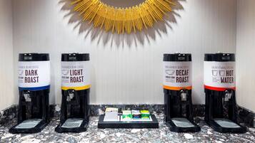 Quatro máquinas de café em uma bancada, com cápsulas de café na frente.