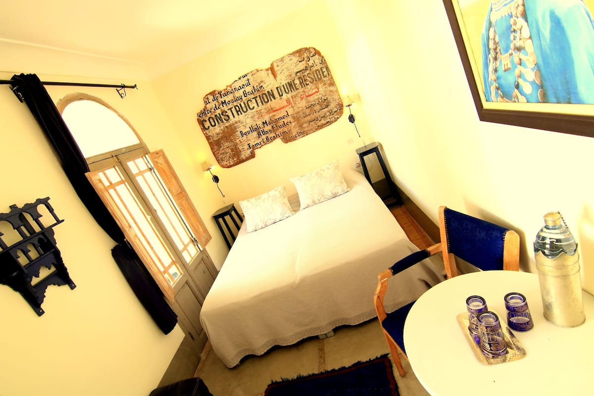 Quarto com cama, mesa com copos e parede com texto.