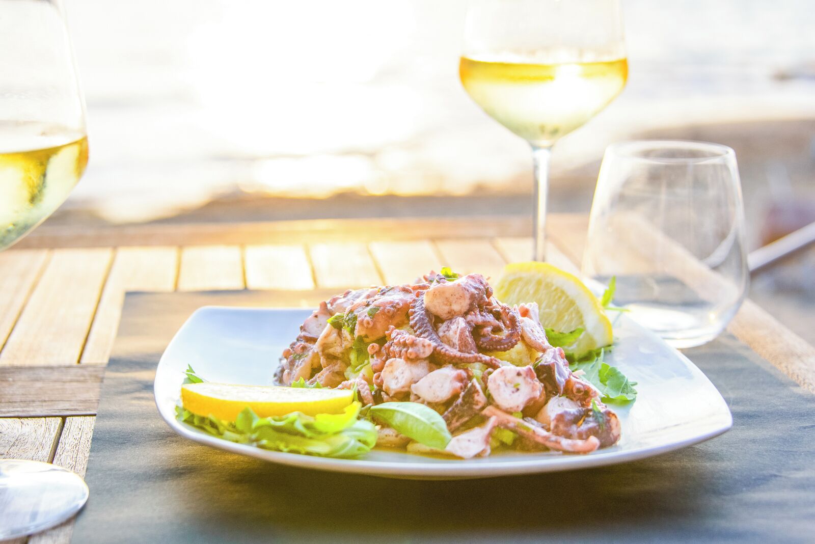 Prato de frutos do mar com um copo de vinho branco e uma fatia de limão.