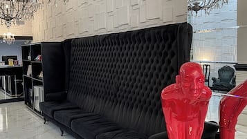 Decoração moderna com sofá preto, lustre e estátuas vermelhas.