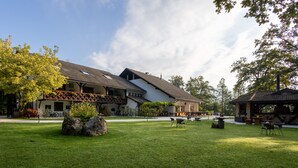 Um edifício com telhado inclinado, varanda coberta e gramado bem cuidado.