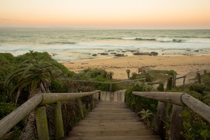 Perto da praia, areia preta, espreguiçadeiras, guarda-sóis 