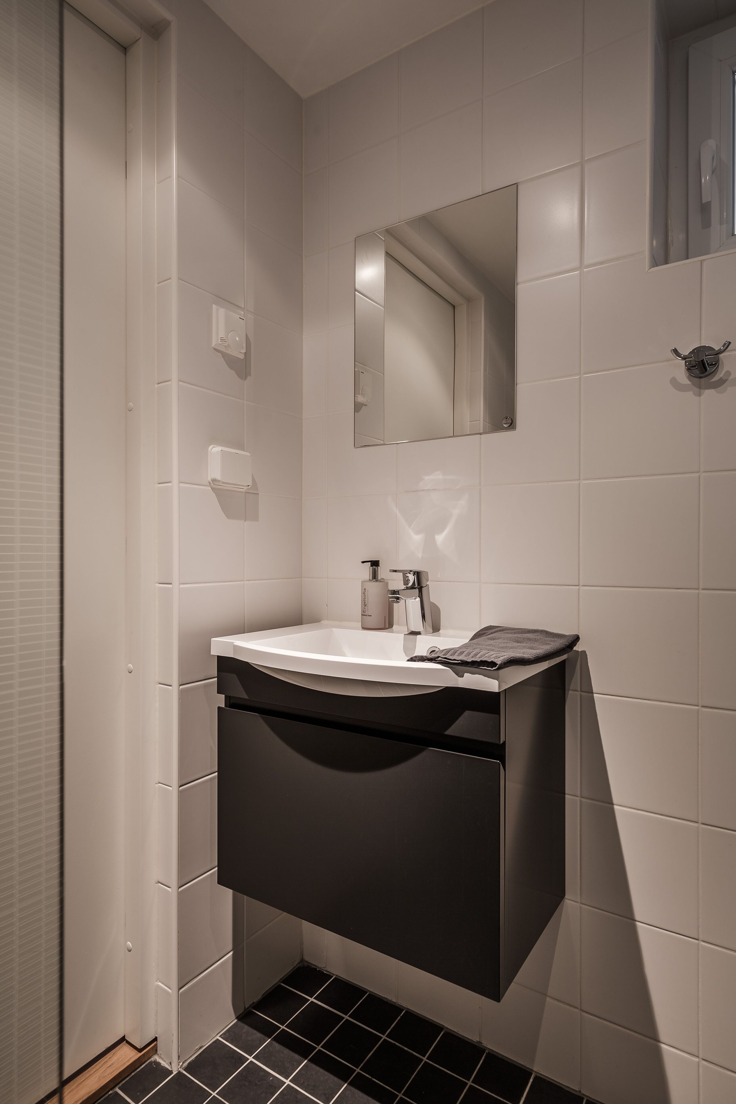 Uma casa de banho moderna com lavatório branco, armário escuro e espelho sobre o lavatório.