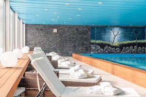 Uma área de spa com cadeiras de descanso, piscina e um mural.