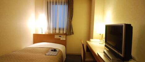 Quarto de hotel com cama, escrivaninha, televisão e janela com cortinas.