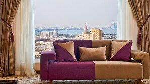 Quarto com uma janela grande que oferece vista para a cidade, um sofá com almofadas e cortinas.