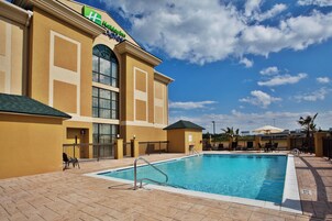 Hotel com piscina, área de estar externa e céu ensolarado.