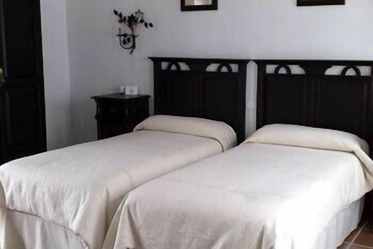 Cama de casal com cabeceira escura e mesa de cabeceira com abajur.