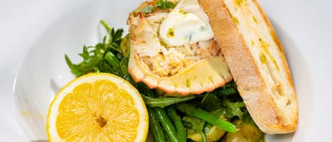 Um prato com um ensopado de frutos do mar, vagem e uma fatia de limão.