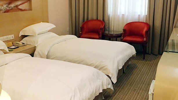 Quarto de hotel com duas camas, uma escrivaninha, uma cadeira e uma pequena mesa.