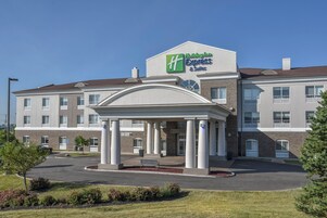 Um hotel Holiday Inn Express & Suites com um pavilhão de entrada central, várias janelas e fachada de tijolos.