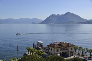 Um edifício à beira do lago, com um cais, barcos e montanhas ao fundo.