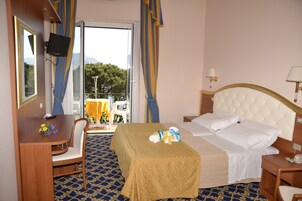 Quarto de hotel com cama, escrivaninha, cadeira, televisão e vista para o exterior.