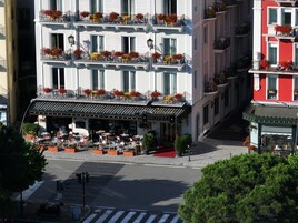 Hotel com área de estar ao ar livre, várias varandas com floreiras e entrada com tapete vermelho.