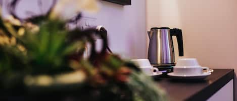 Uma bancada de cozinha com cafeteira, xícaras e uma planta decorativa.