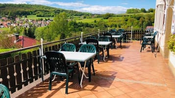 Um terraço com área de estar ao ar livre, chão de azulejos e vista para uma aldeia ao longe.