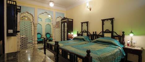 Quarto tradicional com cama, mesa de cabeceira, espelho e um painel decorativo.