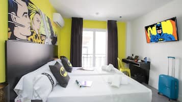 Quarto de hotel com duas camas, uma escrivaninha, uma cadeira, uma mala e obras de arte nas paredes.
