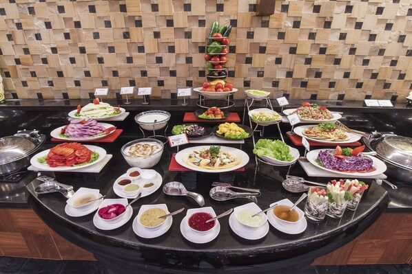 Buffet com diversos pratos e acompanhamentos dispostos em um balcão.