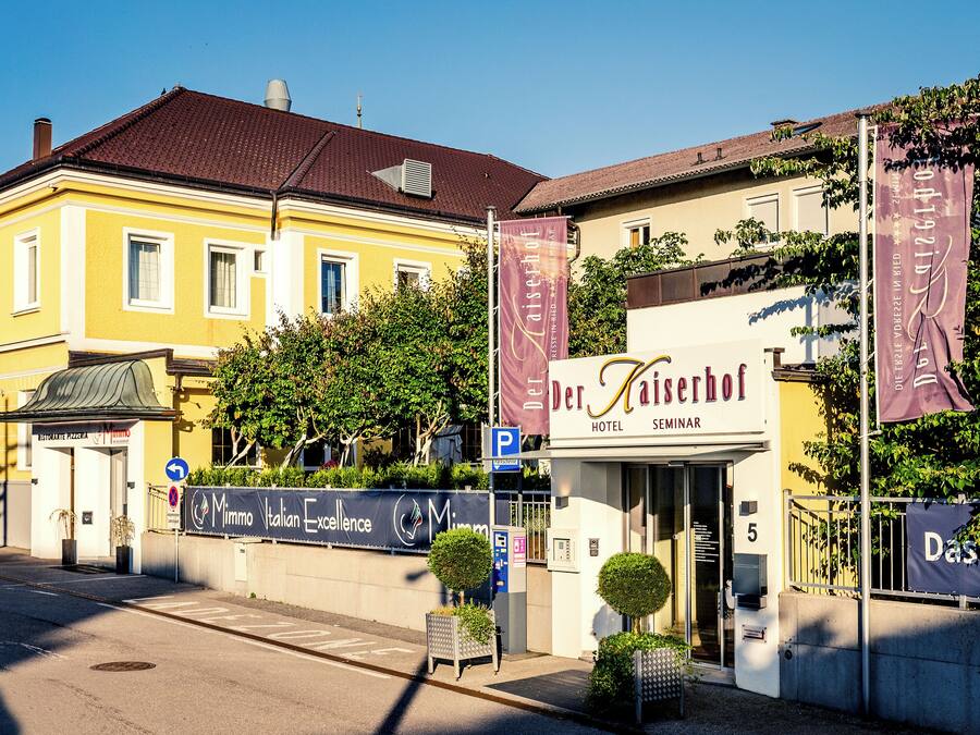 Um edifício amarelo com uma placa indicando 'Der Kaiserhof Hotel' e um cartaz de 'Seminar'.