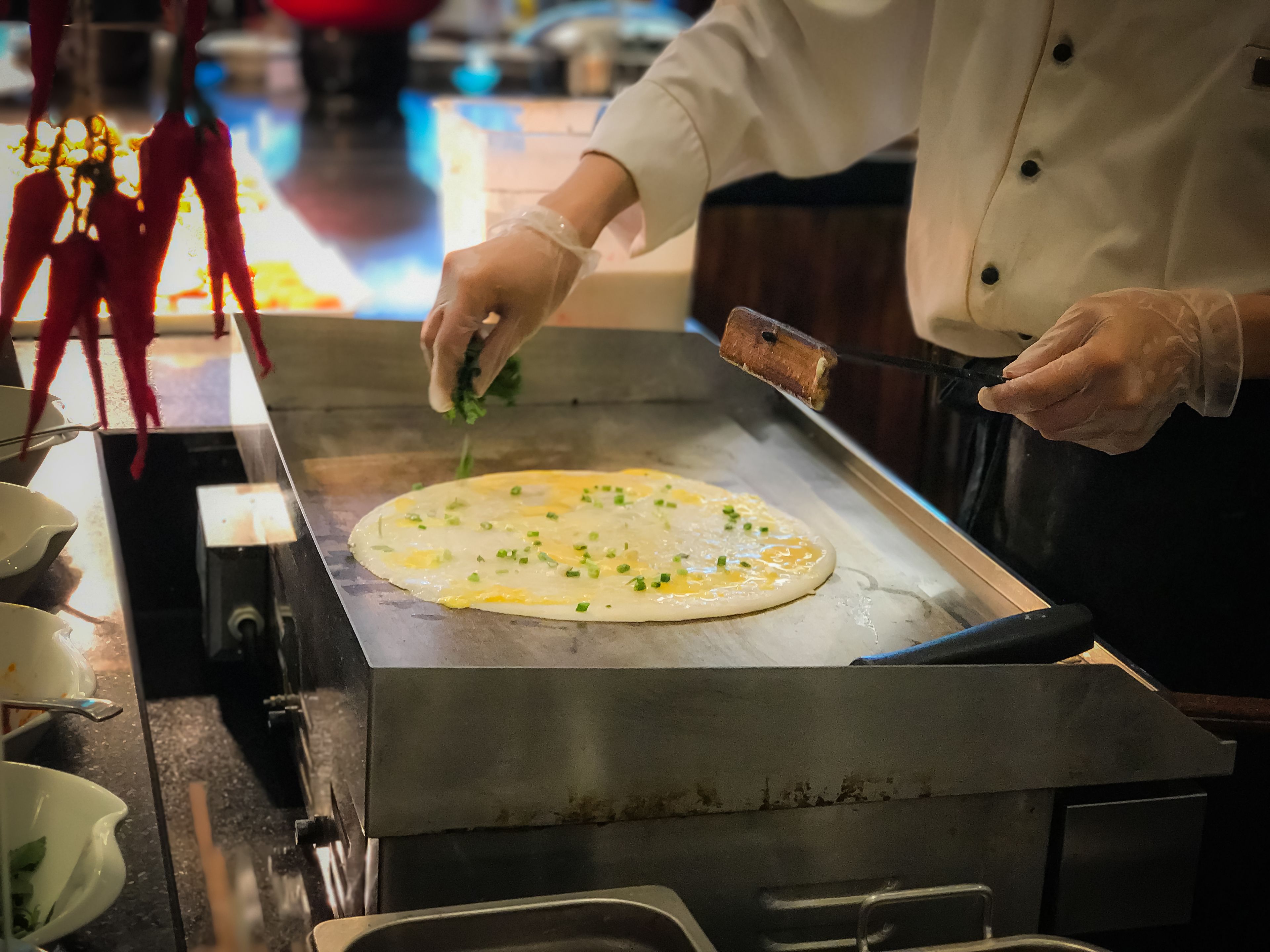 Um chefe de cozinha preparando um prato sobre uma superfície de cozinha plana.
