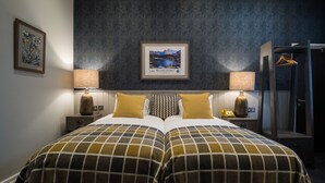 Quarto de hotel com cama, duas mesas de cabeceira, luminárias, um quadro na parede e um guarda-roupa.