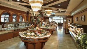 Uma área de buffet com várias estações de comida e elementos decorativos como lustres e obras de arte nas paredes.