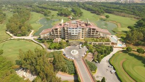 Um hotel grande com vários andares, um pátio central e campos de golfe ao redor.