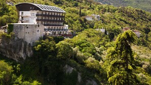 Um hotel com design arquitetônico moderno, localizado numa encosta com vegetação exuberante.