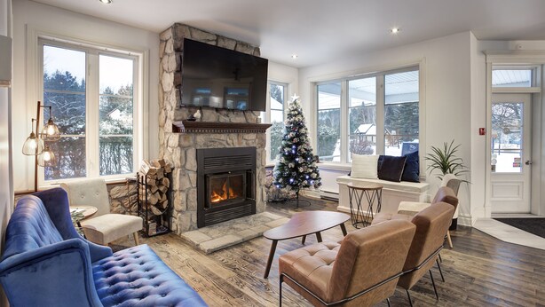Uma sala de estar moderna com lareira de pedra, um sofá azul e um pinheiro de Natal.