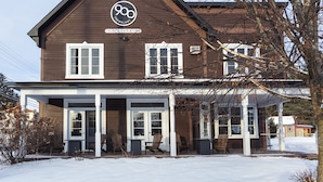 A two-story building with a porch, large windows, and a sign reading "CLOUETTE CAFE-BISTRO".