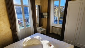 Quarto de hotel com uma cama, mesa de cabeceira, televisão e guarda-roupa.