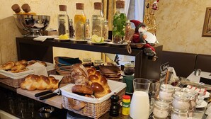 Um buffet com diversos pães, doces e acompanhamentos.