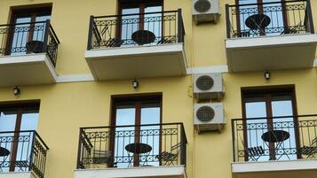 Edifício de vários andares com varandas, unidades de ar condicionado e janelas.